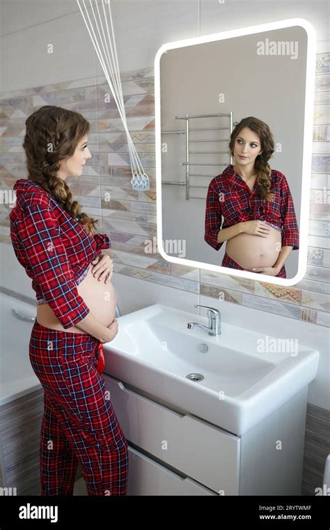 A Pregnant Woman In The Bathroom Looking In The Mirror Female Dressed
