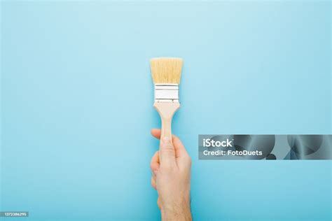 젊은 성인 남자 손 들고 새로운 페인트 브러시 에 밝은 파란색 테이블 배경 파스텔 색상 근접 촬영 가정의 수리 작업을 위한 준비 하향 보기 붓에 대한 스톡 사진 및 기타