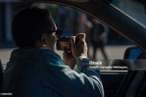 선글라스를 쓴 파파라치 남자 또는 남자가 그녀의 차에 앉아 유명한 사람의 사진을 찍습니다 차에 카메라가 있는 스파이 사립 탐정이나 파파라치 기자가 차 안에 앉아 카메라로