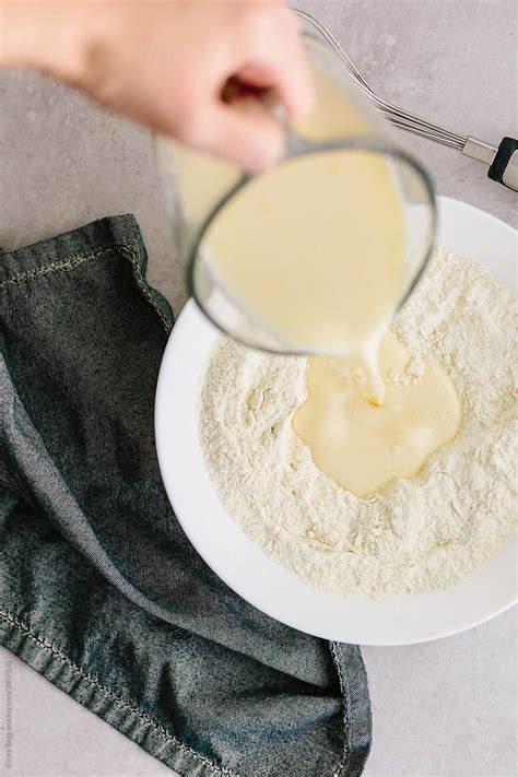 Pouring Milk And Egg Mixture Into Flour To Make Pancake Batter By