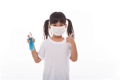 귀여운 아시아 소녀는 마스크를 착용하고 흰색 배경에 질병을 확산 방지하기 위해 알코올로 그녀의 손을 씻는다 인플루엔자 바이러스