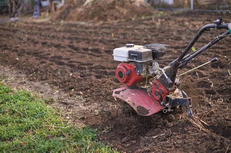 Farming Equipment Tilling Soil In A Rural Field With Red Cultivator And