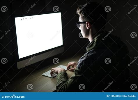 Closeup Of Young Man Sitting And Using Blank Screen Computer In Dark Room Hacker Or Programmer