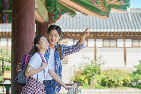 한국의 옛날 전통 가옥의 화려한 색상의 처마 밑에서 여행하고 있는 젊은 아시아 한국 남녀 모델 фотография Stock