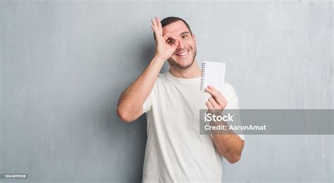 손가락을 통해 찾고 눈에 손으로 확인 서명 하 고 웃 고 행복 한 얼굴로 그런 지 회색 벽 보여주는 노트북에 젊은 백인 남자