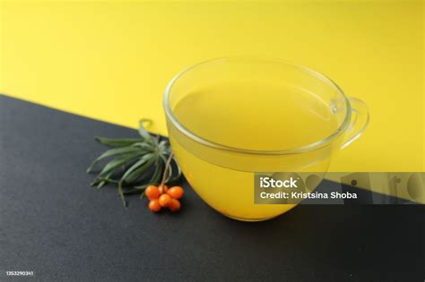 검은 색 노란색 밝은 배경에 바다 갈매 나무 속 차 음료 바다 갈매나무는 바다 갈매나무가 검은 색과 노란색 배경에 오렌지 열매를 잎 바다 갈매 나무의 주물 옆에 유리 컵에