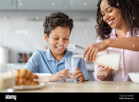 Loving african american mother pouring milk for her son Stock Photo - Alamy
