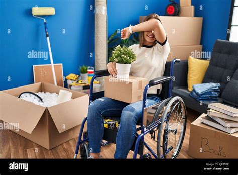 Young Woman Sitting On Wheelchair Moving To A New Home Smiling Cheerful