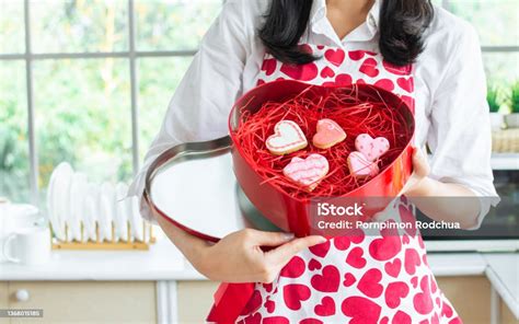 발렌타인 데이에 축하하기 위해 선물이나 선물에 대한 하트 쿠키와 비스킷그릇을 들고 선택 적 초점 손 집에서 부엌에 서있는 여성의