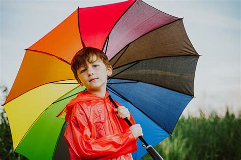 공원에서 무지개 우산을 들고 웃고 있는 여학생의 초상화 아이는 어깨에 화려한 우산을 들고 있다 야외에서 멀티 컬러 우산을 들고