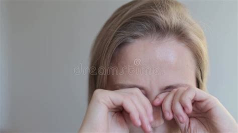 An Attractive European Woman With Blue Eyes Rubs Them With Her Hands