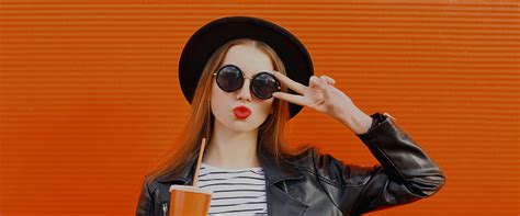 검은 둥근 모자를 쓰고 주스 컵을 가진 세련된 젊은 여성의 초상화 오렌지 색 배경에 재킷 20 29세에 대한 스톡 사진 및 기타 이미지 20 29세 25 29세 가을