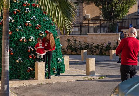 가족의 아버지는 이스라엘 북부의 하이파 도시에서 장식 된 크리스마스 트리의 배경에 대해 어린 딸과 함께 어머니의 사진을 찍습니다 12월에 대한 스톡 사진 및 기타 이미지