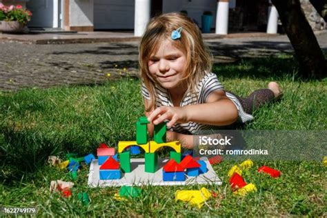 어린 미취학 아동이 야외 탁자 위에서 나무 블록을 가지고 놀고 있다 어린 아이들을 위한 교육용 게임 행복한 아이는 나무 무지개 쌓기 블록으로 탑을 쌓는다 학습에 대한 스톡