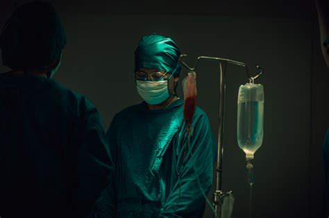현대 수술실에서 수술 수술을 수행하는 아시아 의료 팀 병원에서 일하는 녹색 유니폼 농축액을 입은 의사와 간호사 40 44세에