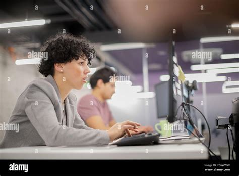 Young Female Software Developer Using Desktop Computer While Writing Programming Code At Modern