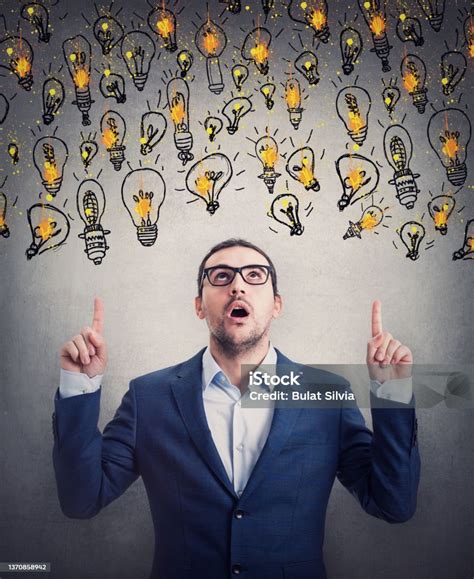 깜짝 놀란 사업가가 검지 손가락을 가리키며 여러 전구가 머리 위로 떠다니는 것을 보고 충격을 받았다 다양한 창의적인 아이디어에서 선택하는 감동비즈니스인 위에에 대한 스톡