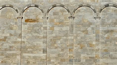 가느다란 기둥으로 지지되는 일련의 블라인드 아치가 있는 대리석 벽의 한 부분으로 자연석 변형과 흰색과 베이지 색이 혼합되어 있습니다 0명에 대한 스톡 사진 및 기타 이미지