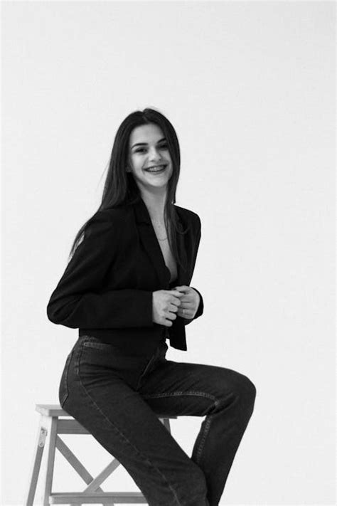 검은 색 양복 모델 미소 짓는 블랙 앤 화이트 수직 쐈어 스툴 의자 스튜디오 촬영 여성 패션 사진에 관한 무료 스톡 사진