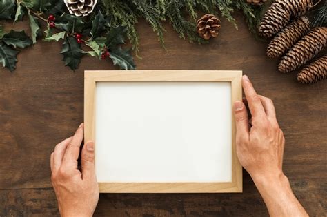 Persona Que Sostiene El Marco En Blanco En La Mesa Foto Gratis