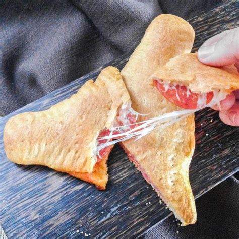 A Person Is Cutting Into Two Pastries On A Wooden Board