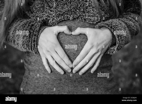 man holding the belly of his pregnant wife who makes a heart. Pregnant ...