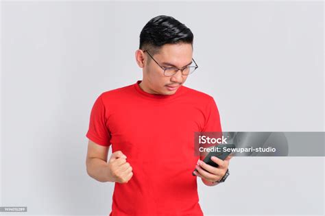 화난 젊은 아시아 남자가 휴대 전화를 사용하여 흰색 배경에 고립 된 가짜 뉴스에 반응합니다 30 34세에 대한 스톡 사진 및