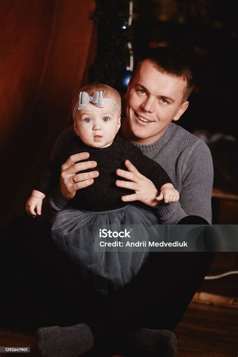 메리 크리스마스와 해피 홀리데이 크리스마스 배경 근처 귀여운 아기 딸 소녀를 껴안고 쾌활한 아버지 아빠와 어린 아이는 집에서 함께 놀고 재미있게 놀고 있습니다 사진 이미지에