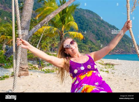 Adult Woman With Long Blonde Hair Swinging On A Swing By The Sea On The Island Of Koh Chang In