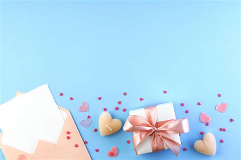 해피 발렌타인 데이 인사말 카드 템플릿입니다 낭만적 인 편지 선물 상자 하트 모양의 양초 파스텔 블루 테이블에 색종이가있는