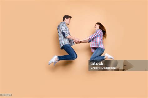 전체 길이 프로필 사진 두 사람 미친 여자 남자 점프 높은 보유 손 쾌활 한 장난 분위기 착용 캐주얼 격자 무늬 청바지 옷 고립