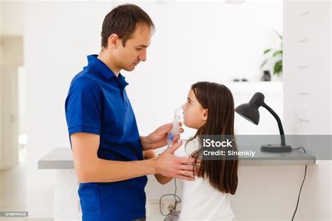 집에서 분무기로 흡입하는 어린 유아 소녀 아버지가 장치를 돕고 들고 계십니다 독감 기침 및 기관지염을 가진 아이 천식 흡입기 흡입 증기 아픈 개념 2명에 대한 스톡 사진 및