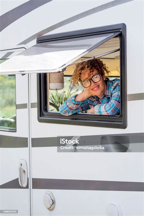 행복한 관광객은 창문 밖에서 카메라를 바라보는 현대적인 캠핑카 안에서 여행 휴가를 즐깁니다 대안적인 무료 유목민 생활 방식은 캠핑카입니다 어드벤쳐 홀리데이 밴라이프 밀레니엄