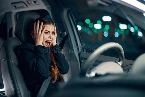 Frightened Woman Is Sitting Behind The Wheel Of A Car In A Black Shirt