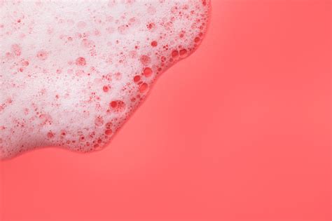 분홍색 배경에 거품이 있는 하얀 거품의 질감 세척 위생 샴푸 비누 목욕 젤 무스를위한 화장품 거품 최소한의 미용 및 의료 배경