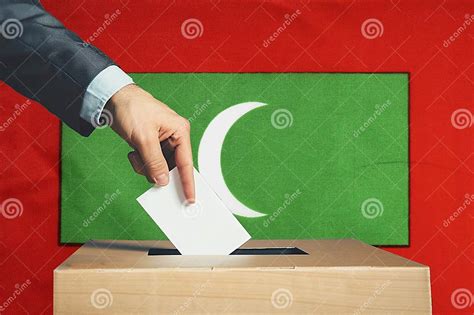 A Hand Holds A Ballot Paper In A Ballot Box Against The Background Of
