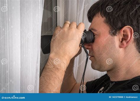 Luomo Sta Spiando I Suoi Vicini Con Il Binocolo Fotografia Stock