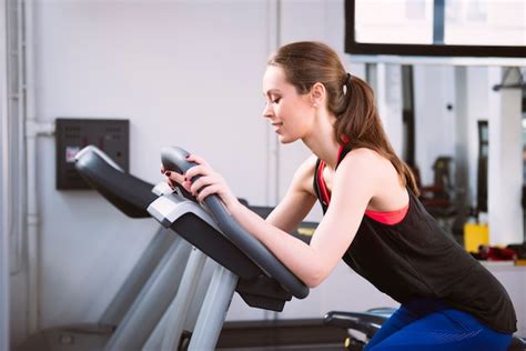 Premium Photo Smiling Woman Riding An Exercise Bike In Gym