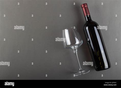 Corked Bottle Of Red Wine And Empty Wine Glass On Gray Background