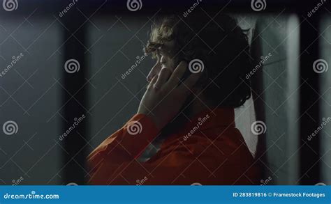 Criminal In Orange Uniform Talks On Phone In Prison Cell Stock Footage