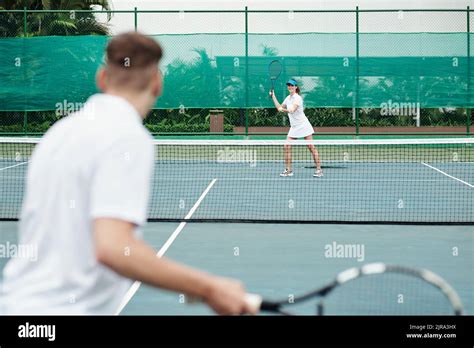 Smiling Young Woman Serving Ball When Playing Tennis With Friend Stock