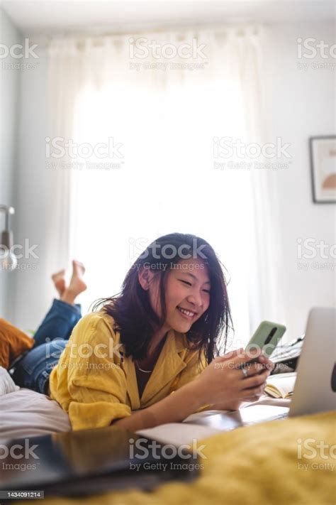 침대에 누워 있는 십 대 소녀가 전화를 사용하여 문자 메시지를 보냅니다 소셜 미디어 앱을 사용하는 젊은 여성 공간을 복사합니다