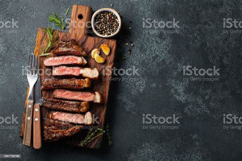 얇게 썬 스테이크 Striploin 후추 구운 마늘 소금 백 리 향 어두운 돌 배경에 나무도 마 보드에 제공 됩니다 복사 공간