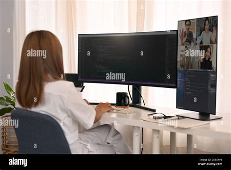 Rear View Of Female Developer Having Video Conference And Working With