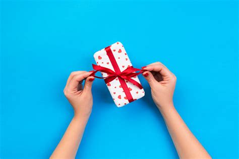 여자 손에 빨간 리본으로 종이에 포장된 발렌타인 또는 다른 휴일 수 제 선물을 제공합니다 블루 테이블에 선물 평면도의 상자 레드 심장 장식 디자인에 대 한 복사 공간 제시