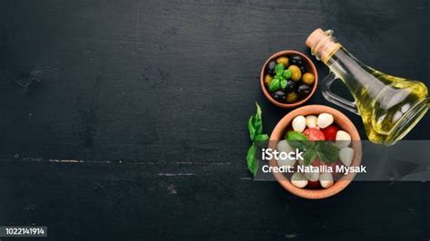 이탈리아 Caprese 샐러드 재료입니다 모 짜 렐 라 치즈 체리 토마토 바 질 잎 올리브 오일 후추 에 검은 나무 배경