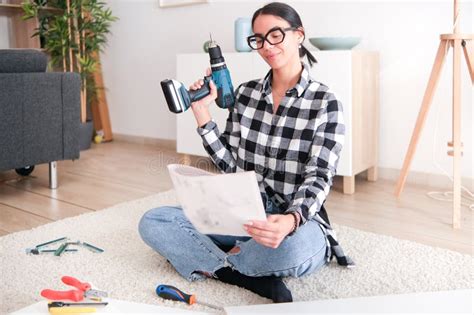 Woman Who Is Assembling Furniture In Her Home As Part Of A Renovation