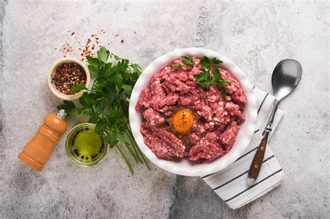 생 다진 고기 밝은 회색 콘크리트 배경에 흰 접시에 고기 쇠고기 돼지 고기 또는 양고기 향신료 허브 및 달걀을 갈아 넣습니다