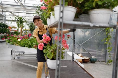 Premium Photo Woman Pushing Cart With Flowers In A Nursery