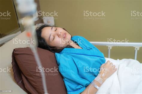 환자 아시아 여성은 식염수로 침대에 누워 병원 병실에서 혈압을 모니터링합니다 수술 후 치료 응급 회복 고혈압과 저혈압 의료 및